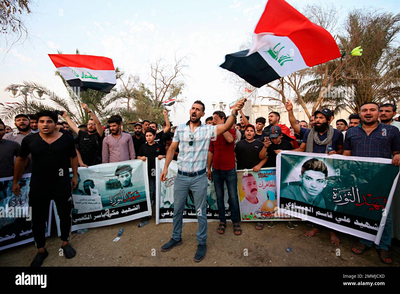 Demonstrators hold national flags and images of protesters who were ...