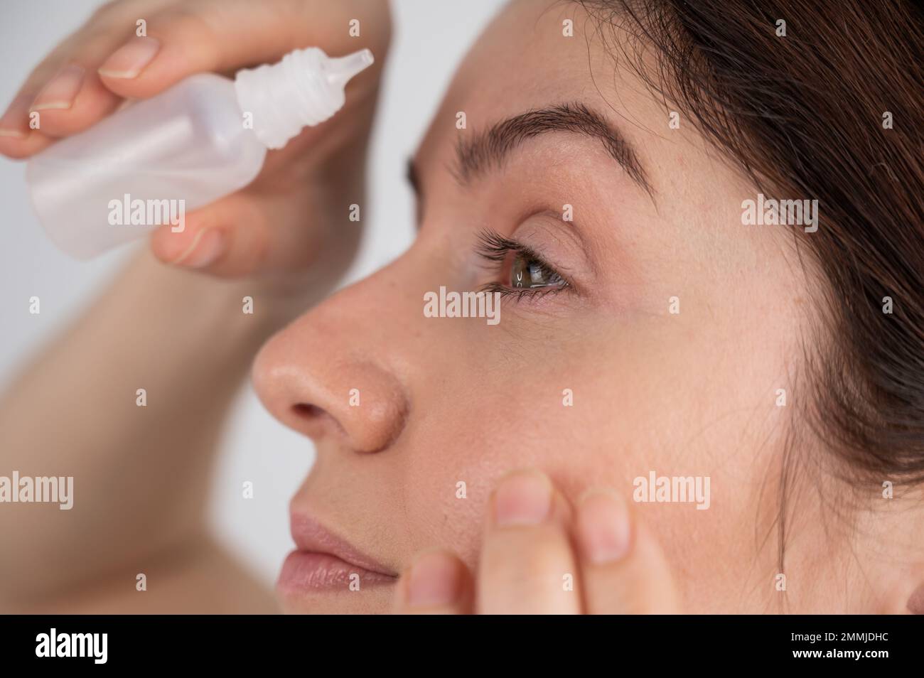 Caucasian woman dripping moisturizing drops into her eyes Stock Photo ...
