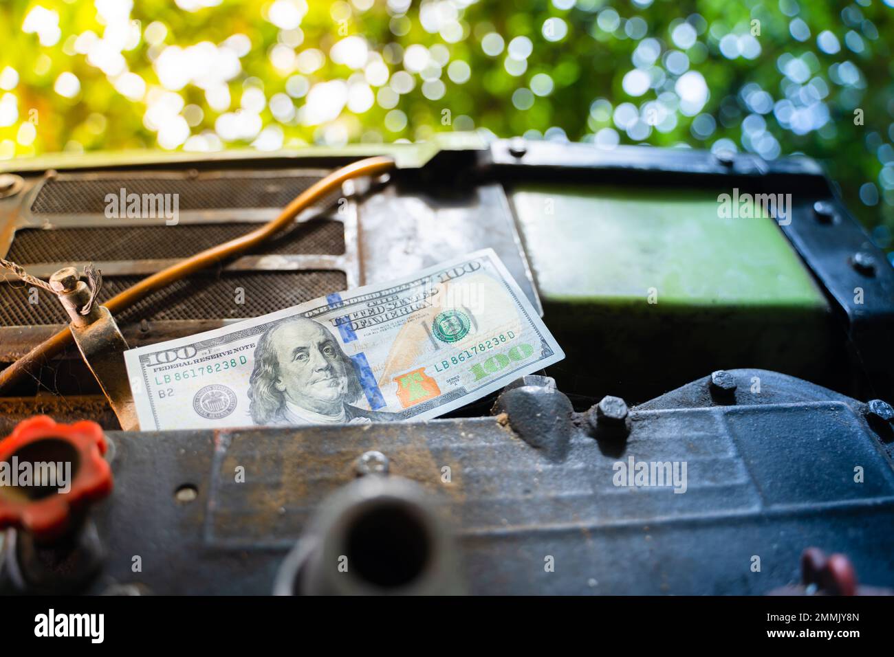 Hundred dollar bill on a tractor engine close-up. Money and the ...