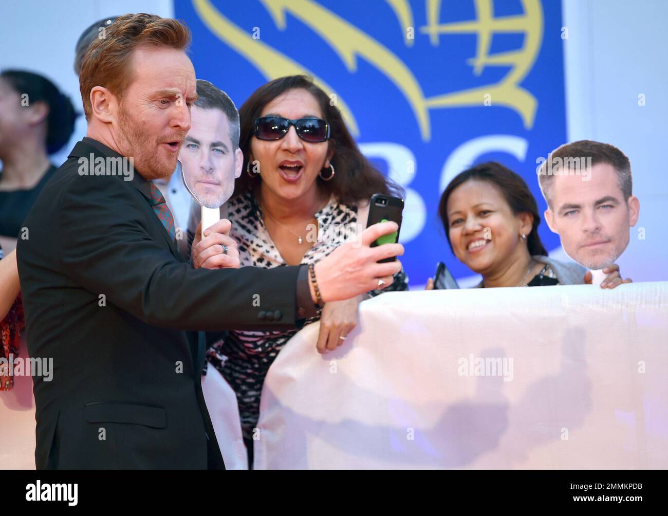 Tony Curran, left, takes a selfie with fans as they hold paper fans ...