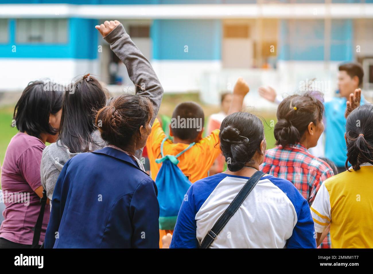 Back view of Moms watch and cheering their sons playing football in ...