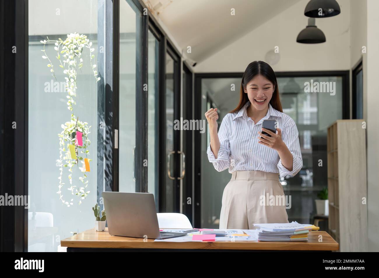 Portrait of happy young business asian woman celebrating success with arms up. positive ...