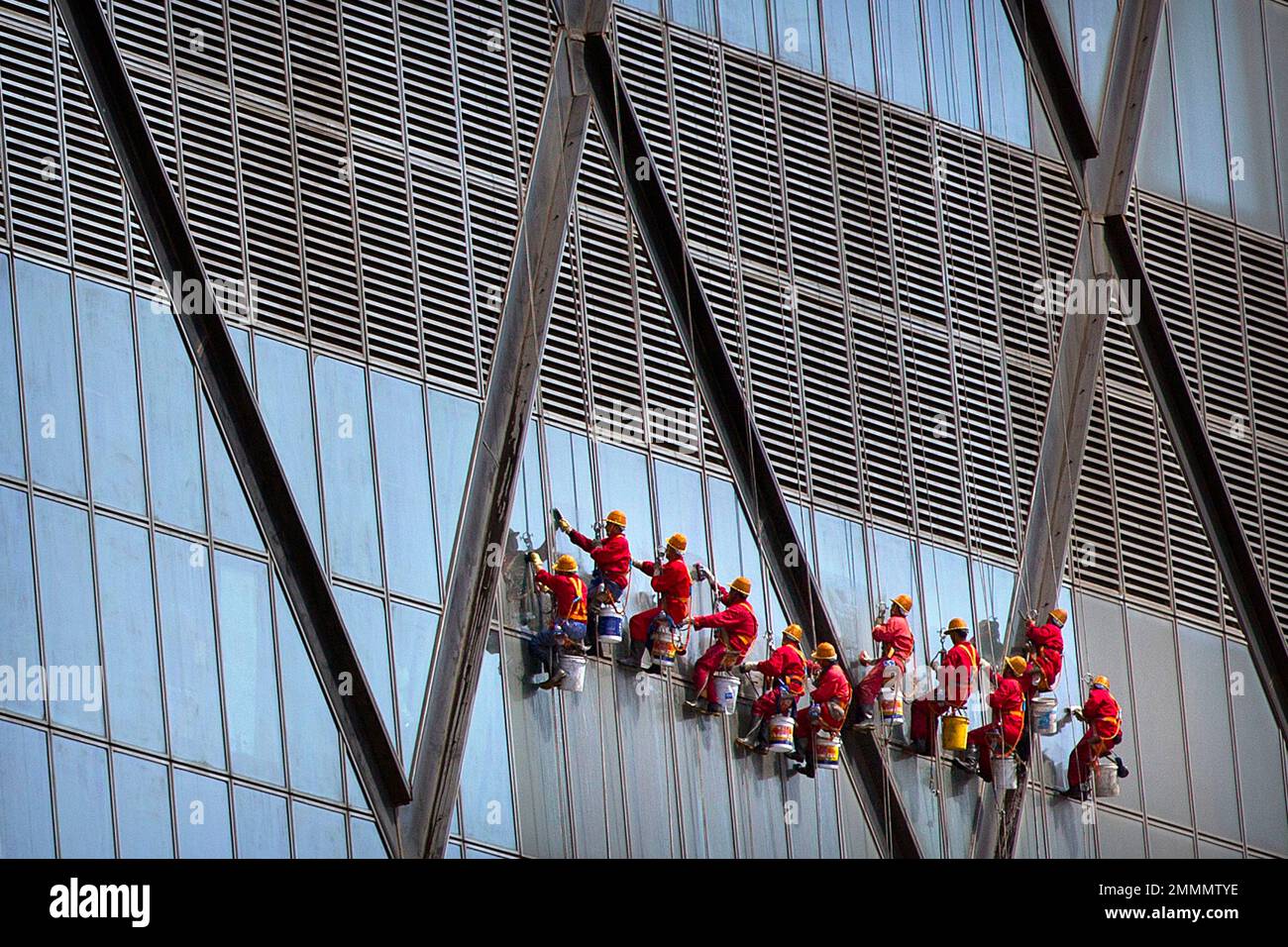 Window washers dangle from ropes as they clean the facade of the China ...