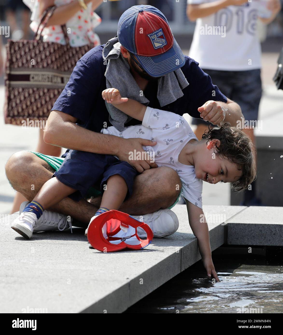 Joseph Setton and his son, Sion Setton, cool off with water from a ...