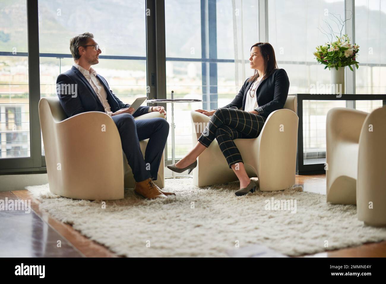 Partners in business. two businesspeople talking in a corporate office ...