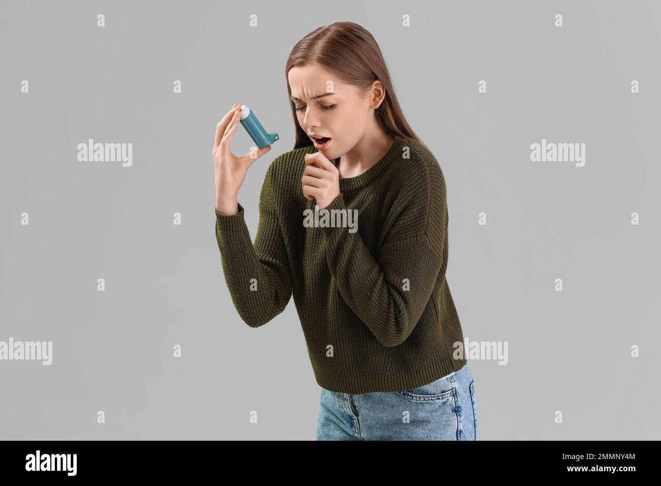Sick young woman with inhaler on grey background Stock Photo - Alamy