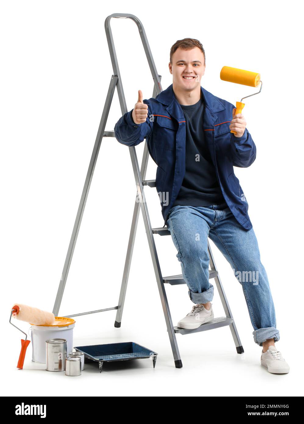 Young man with roller, ladder and cans of paint showing thumb-up on ...