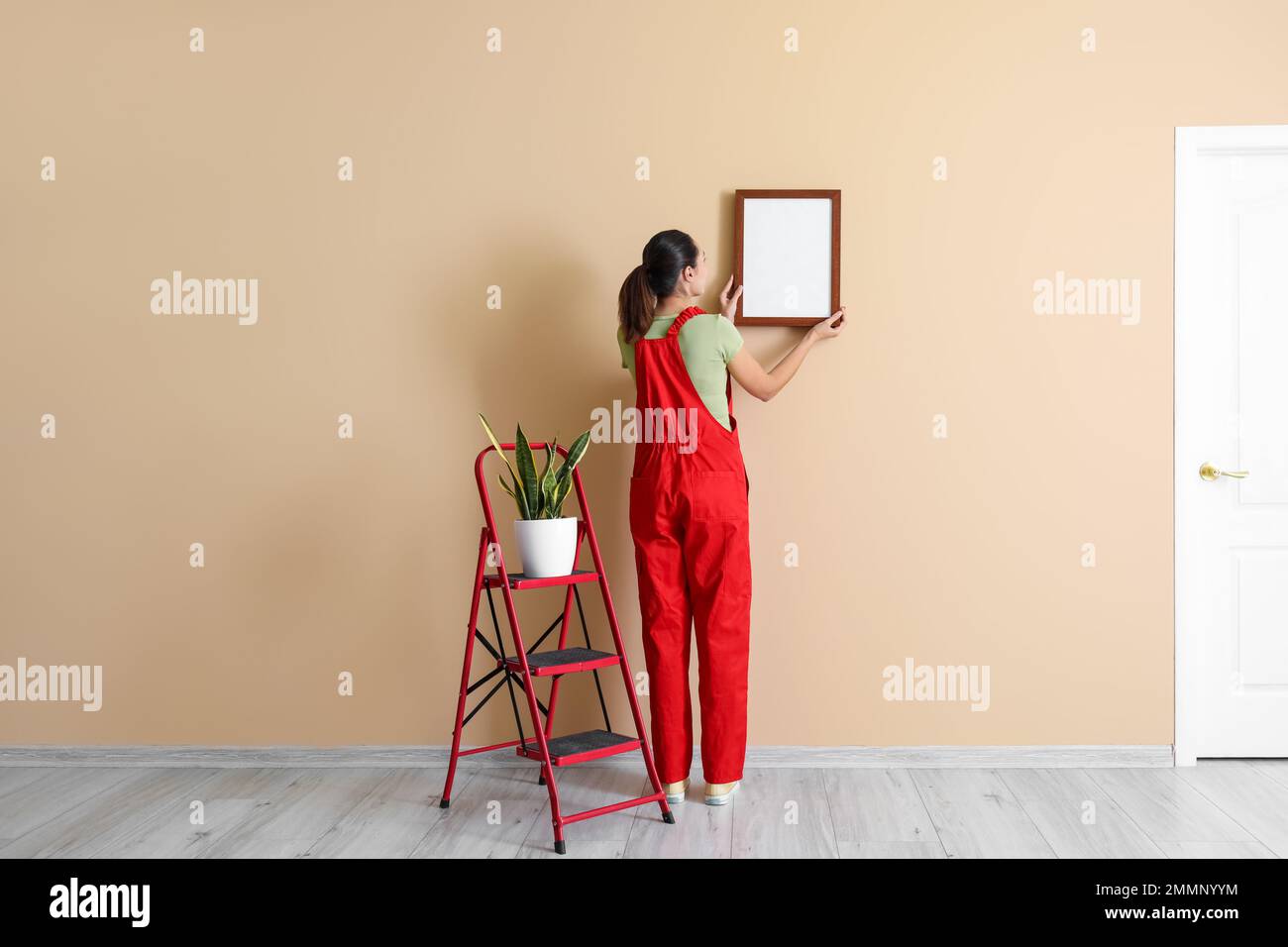 Woman hanging frame on the wall hi-res stock photography and images - Alamy