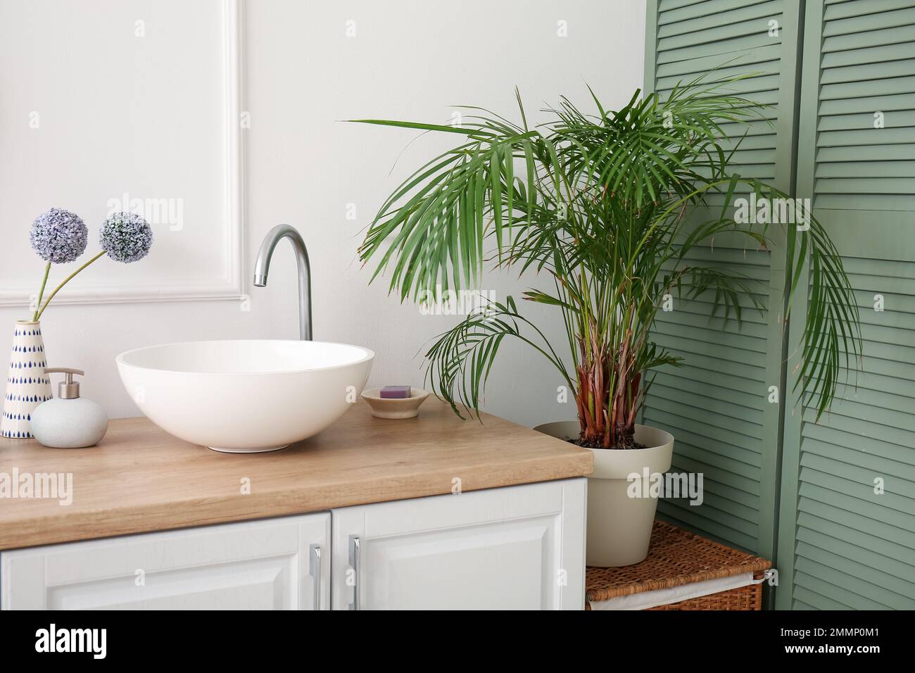 Ceramic sink, vase with flowers and bath accessories on counter in ...