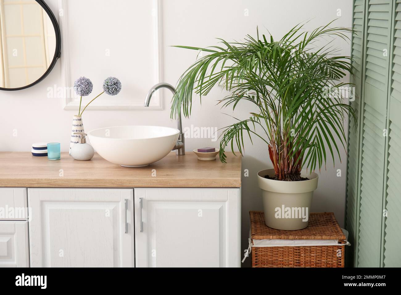 Ceramic sink, vase with flowers and bath accessories on counter in ...