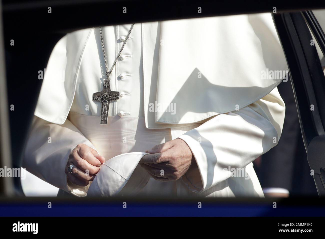 Pope Francis, framed by the window of a car, holds his cap cape as he ...