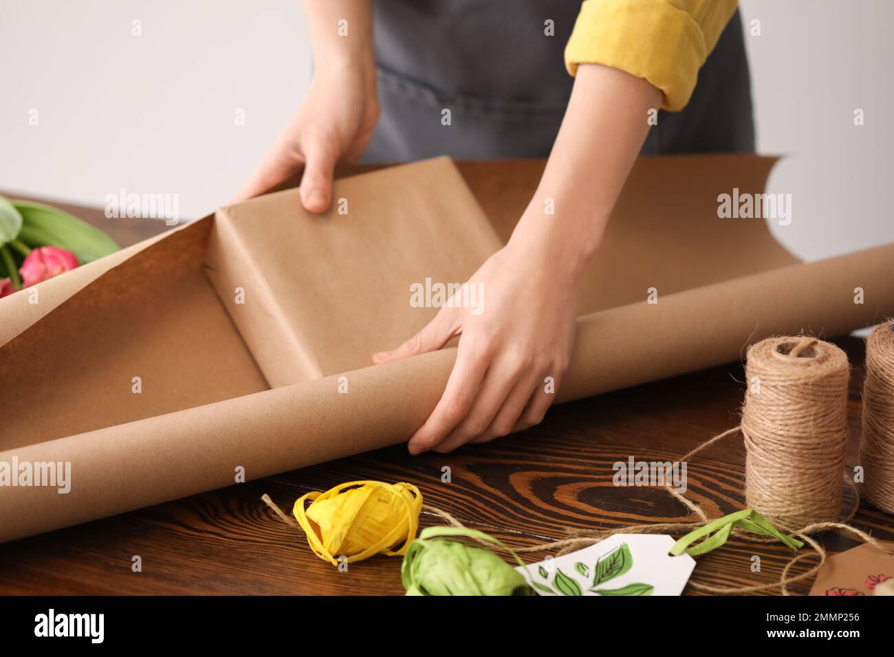 Woman wrapping gift for International Women's Day celebration at wooden ...