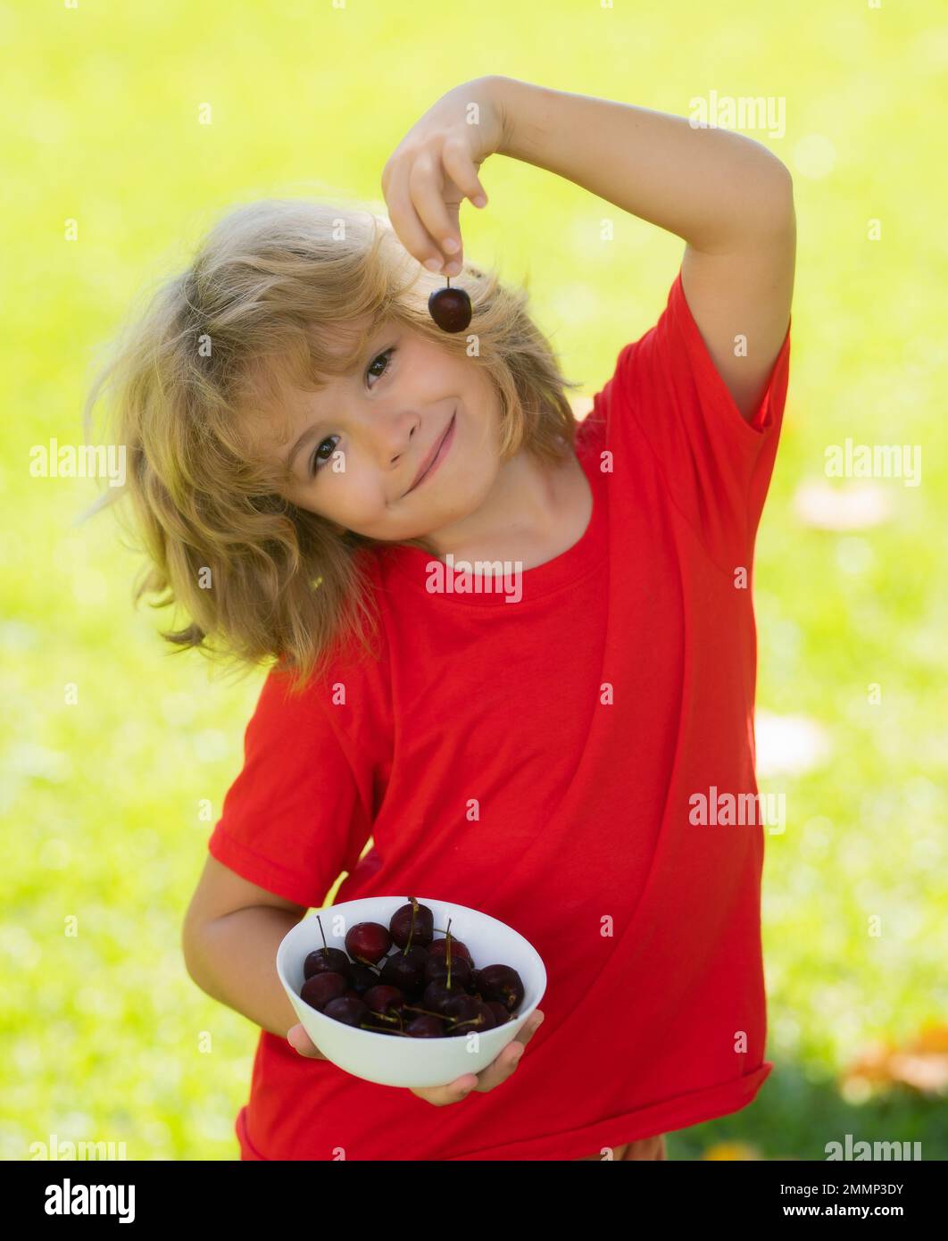 Funny kid in red t-shirt eats cherries. Excited face. Cherry for kids ...