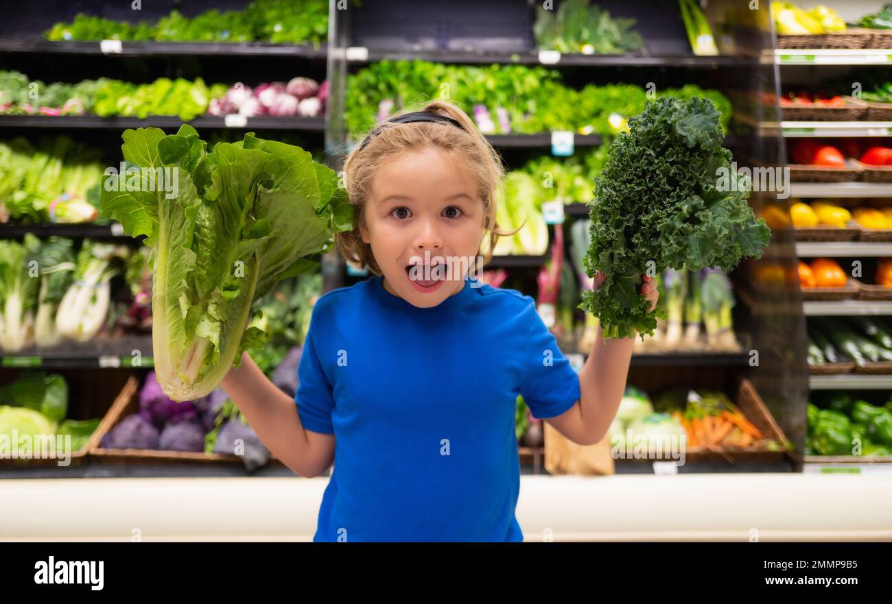 Kid with vegetables at grocery store. Kid choosing food in grocery ...