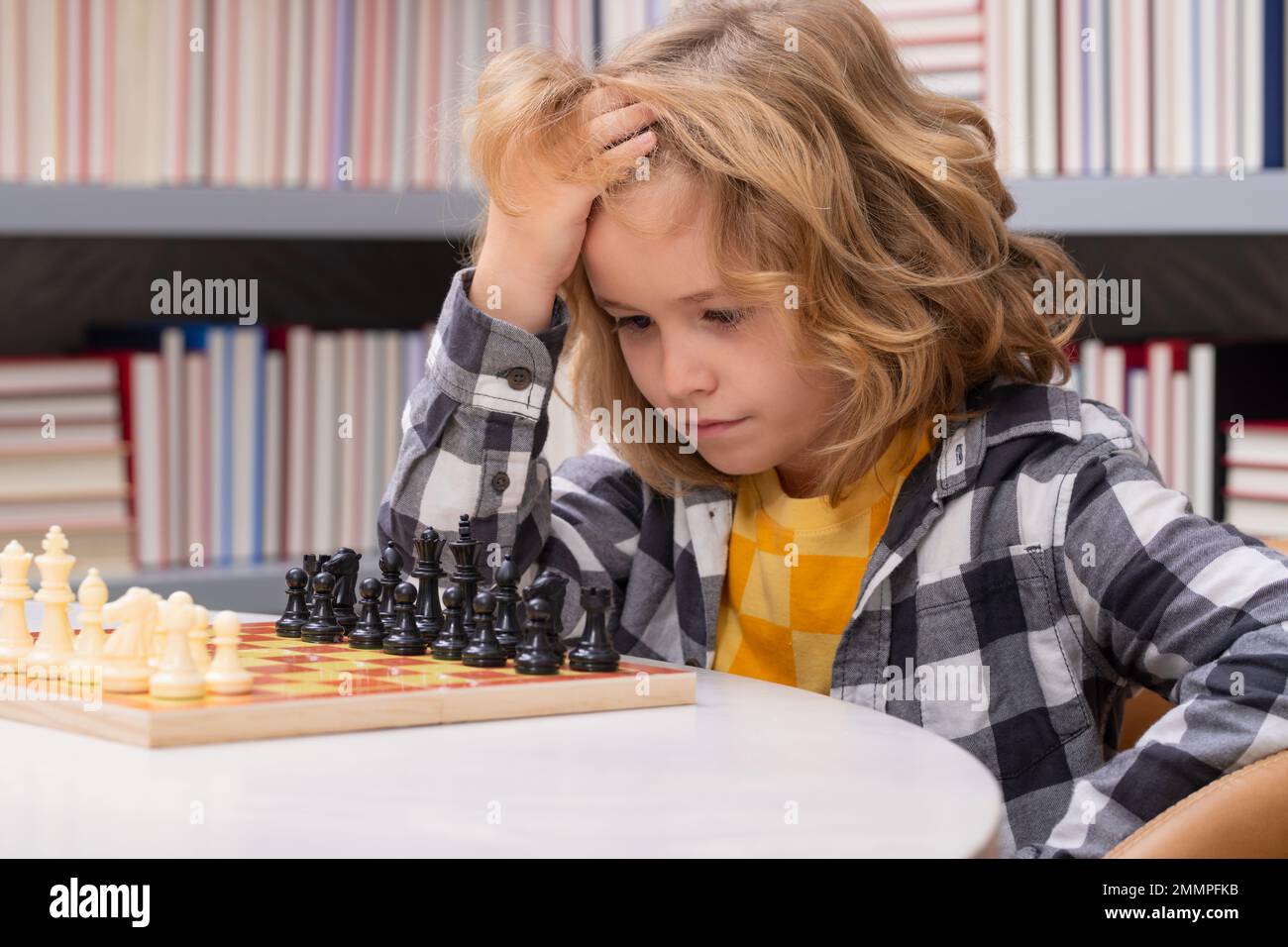 Kid play chess in classroom at school. Clever child thinking about ...
