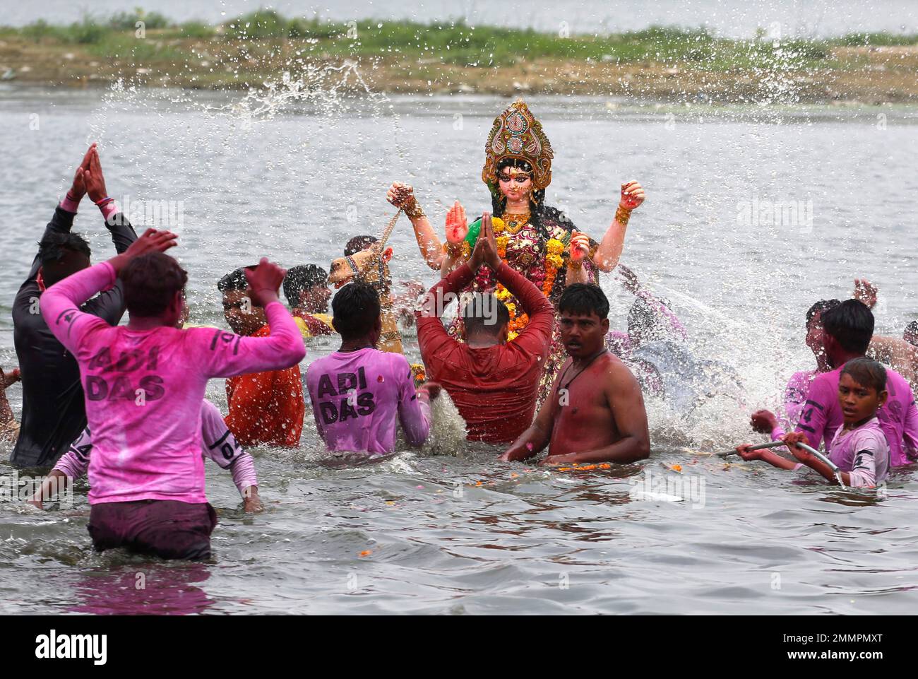 Indian devotees immerse an idol of Hindu goddess Dashama on the bank of ...