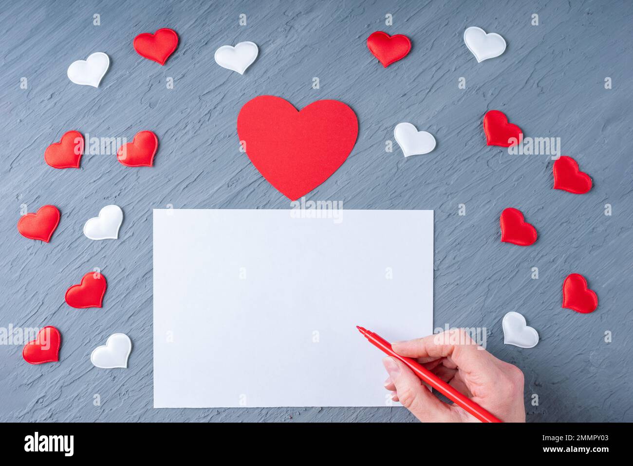 Happy Valentine's Day greetings. Hand holds a red pen to write a love ...