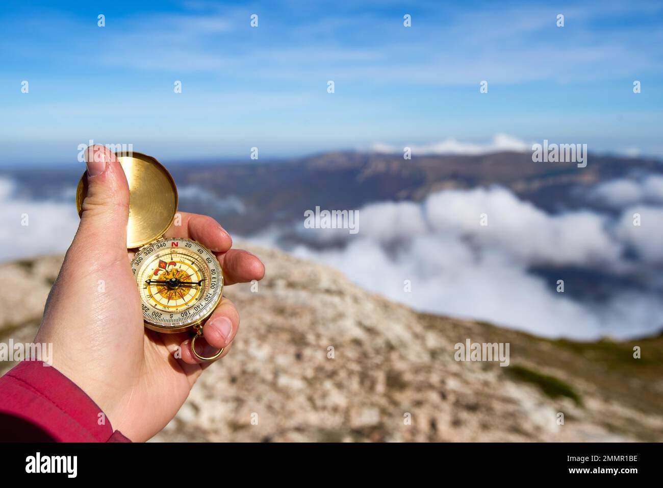 Closeup hand holding compass with mountain and clouds background ...