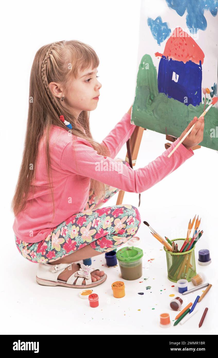 The child draws a house. Children's painting. Little girl draws the sun ...
