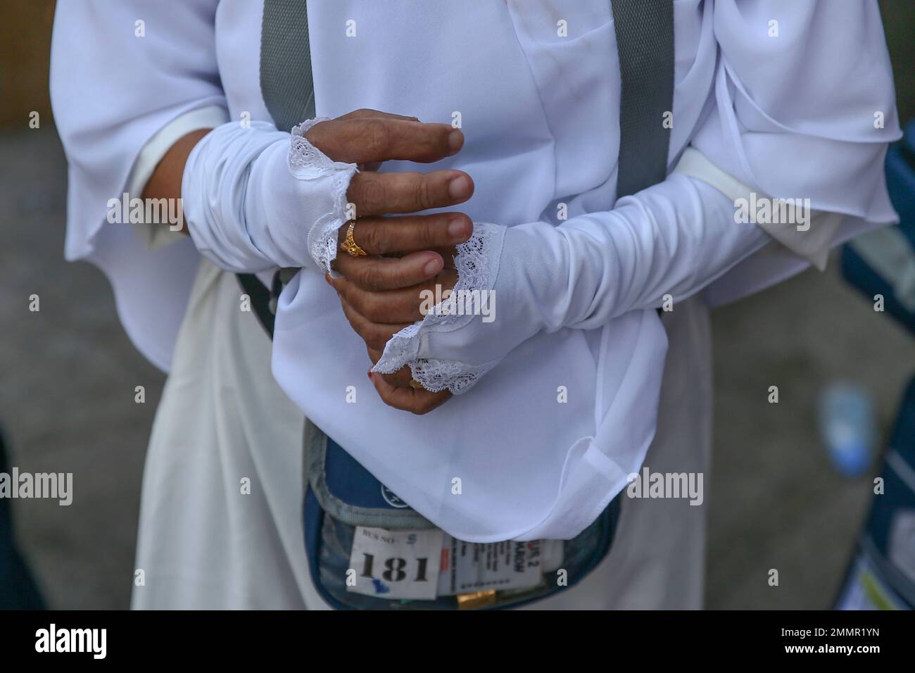 A Muslim pilgrim with her hands covered with decorated white cloth ...