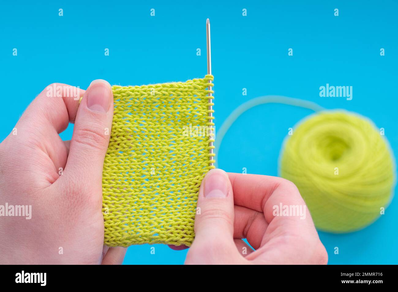 Close up of hands of caucasian woman knitting with green thread on a ...