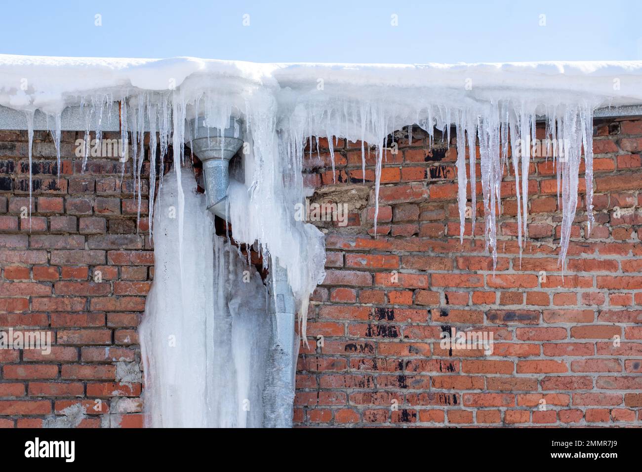 Long transparent icicles hang from the roof. The icy gutter is like a ...