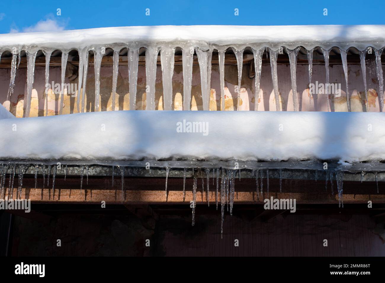 Very beautiful icicles hanging in two rows from the roof of an old ...