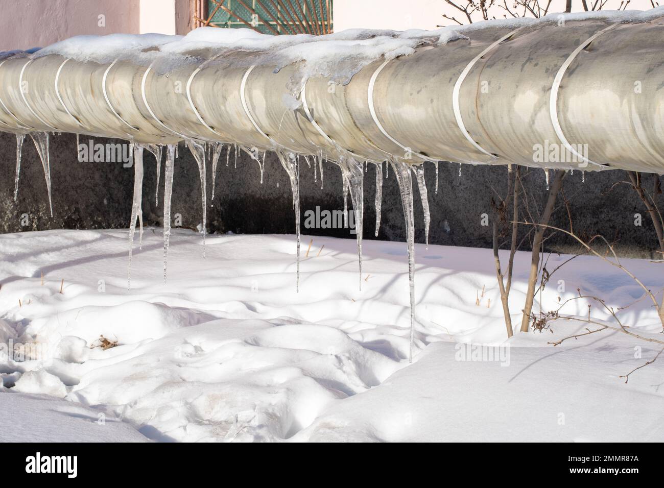 Very beautiful transparent icicles hanging from a snow-covered pipe ...