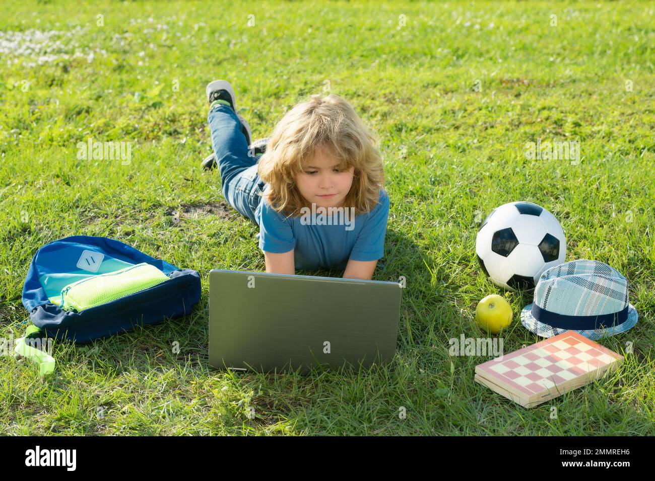 Outdoor education with laptop. Kid lying on grass using laptop notebook ...