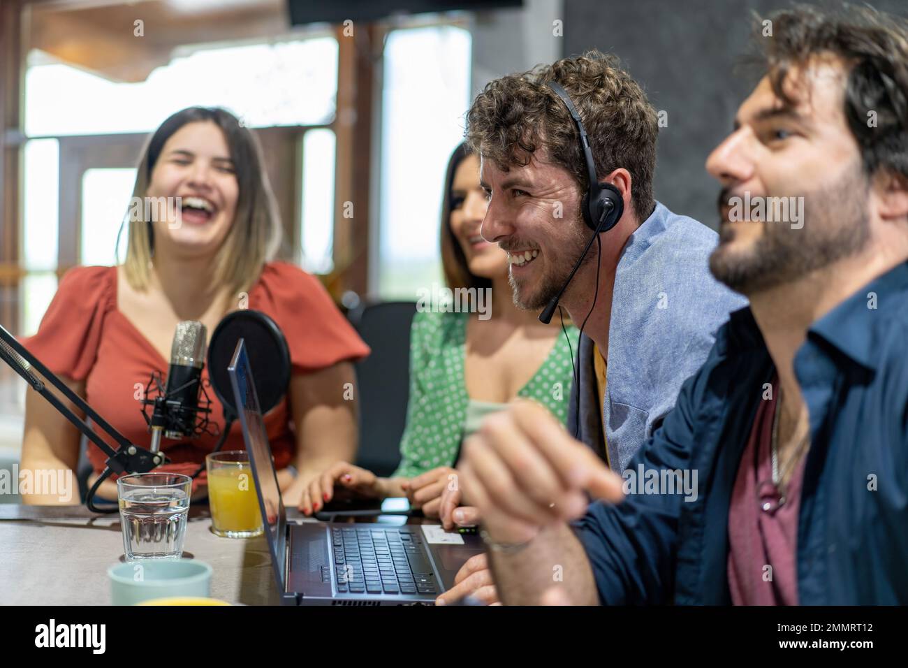 Four young content creators sitting around a table with microphone ...
