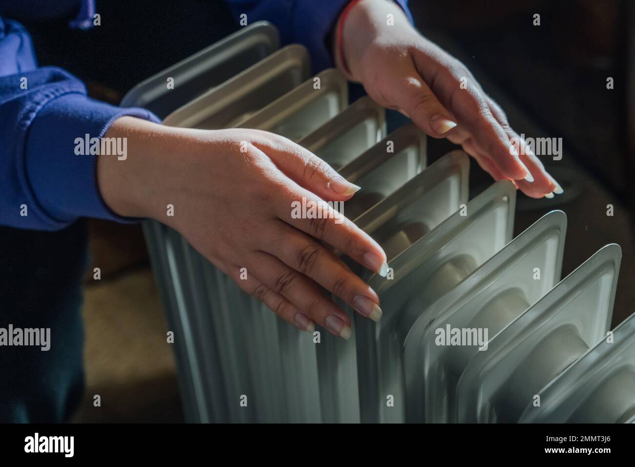 Female hands warming on oil heater at home close up. Cold winter with ...