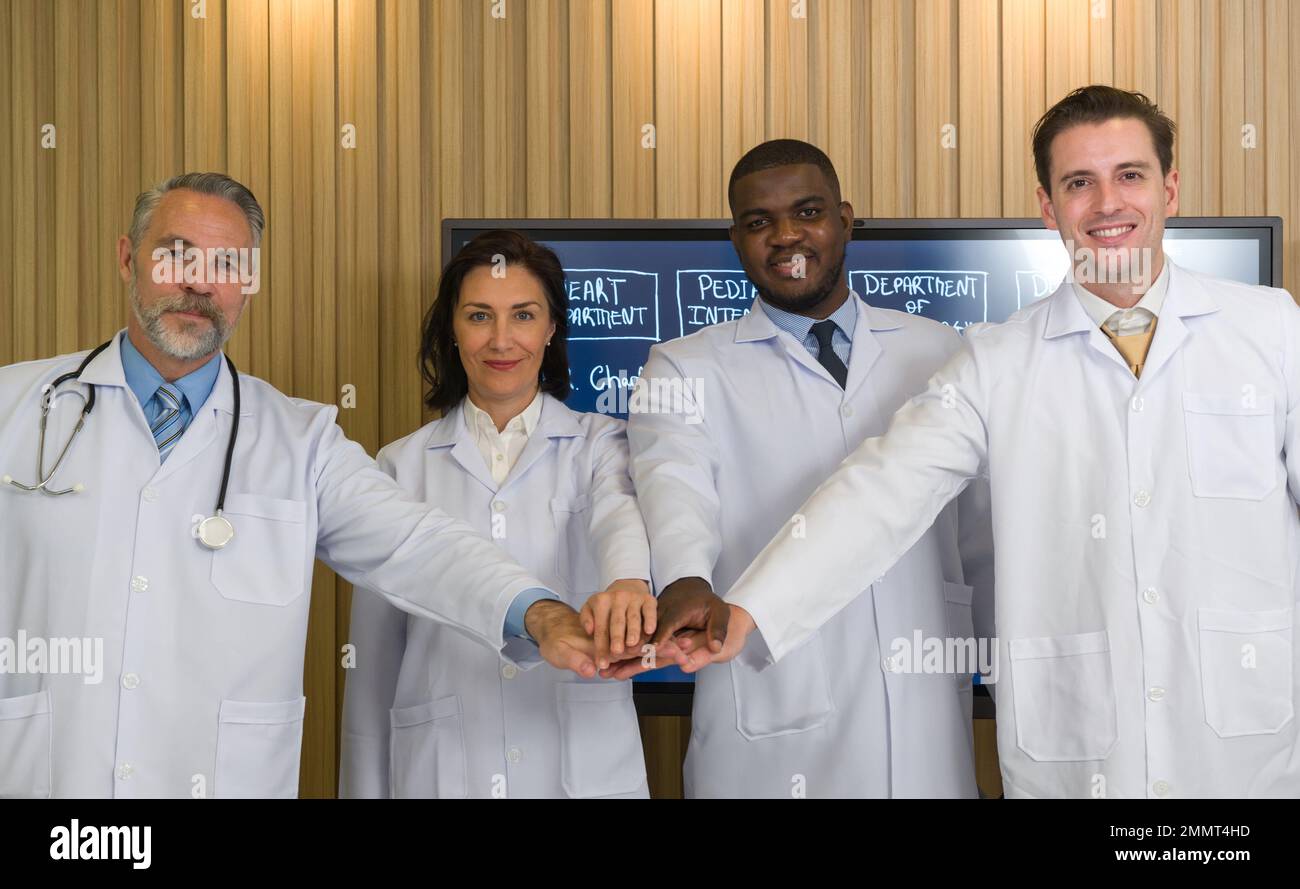 Group of doctors in white gown join hands together with a smile in ...