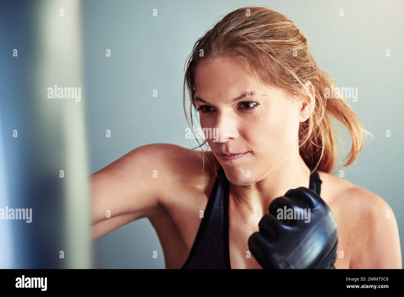 Shes a fierce fighter. a female boxer training with a punching bag ...