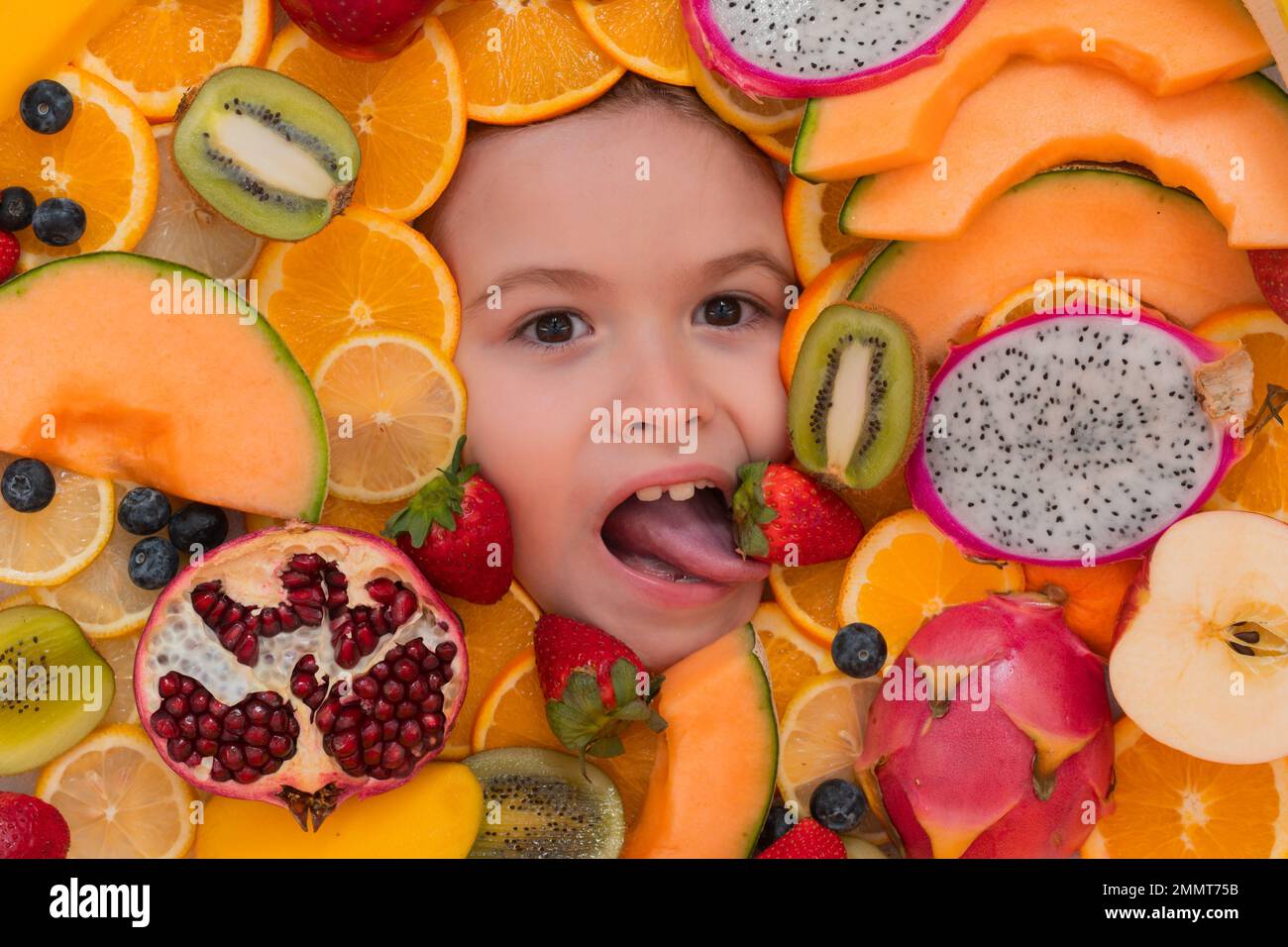 Kid lick strawberry. Frutit and child face close up. Top view of child ...