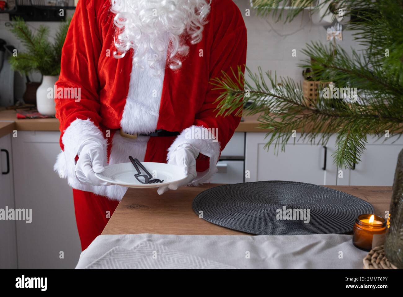 Santa Claus sets the table at home in the white kitchen, puts a plate ...