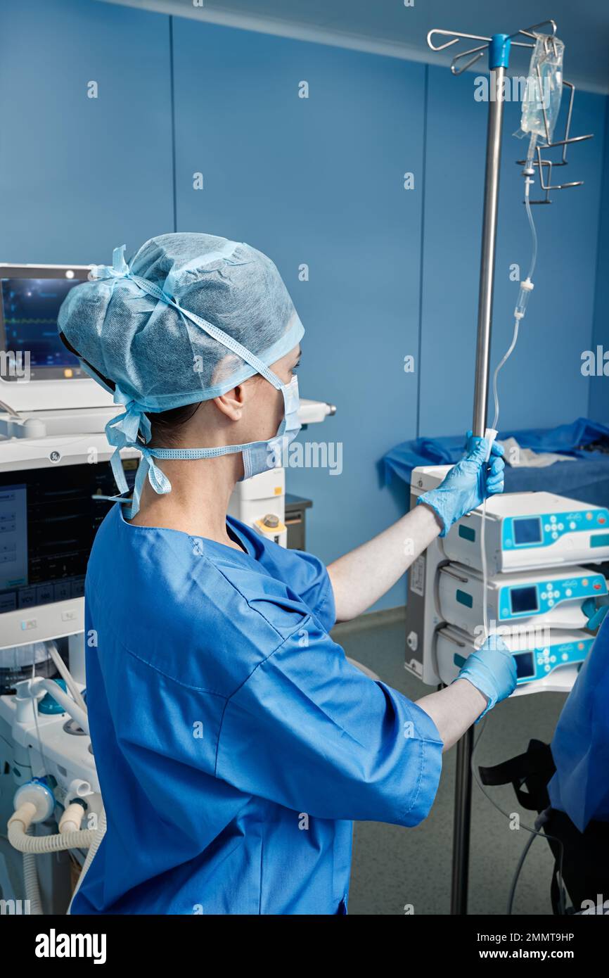 Surgery nurse wearing protective uniform preparing medical dropper for ...