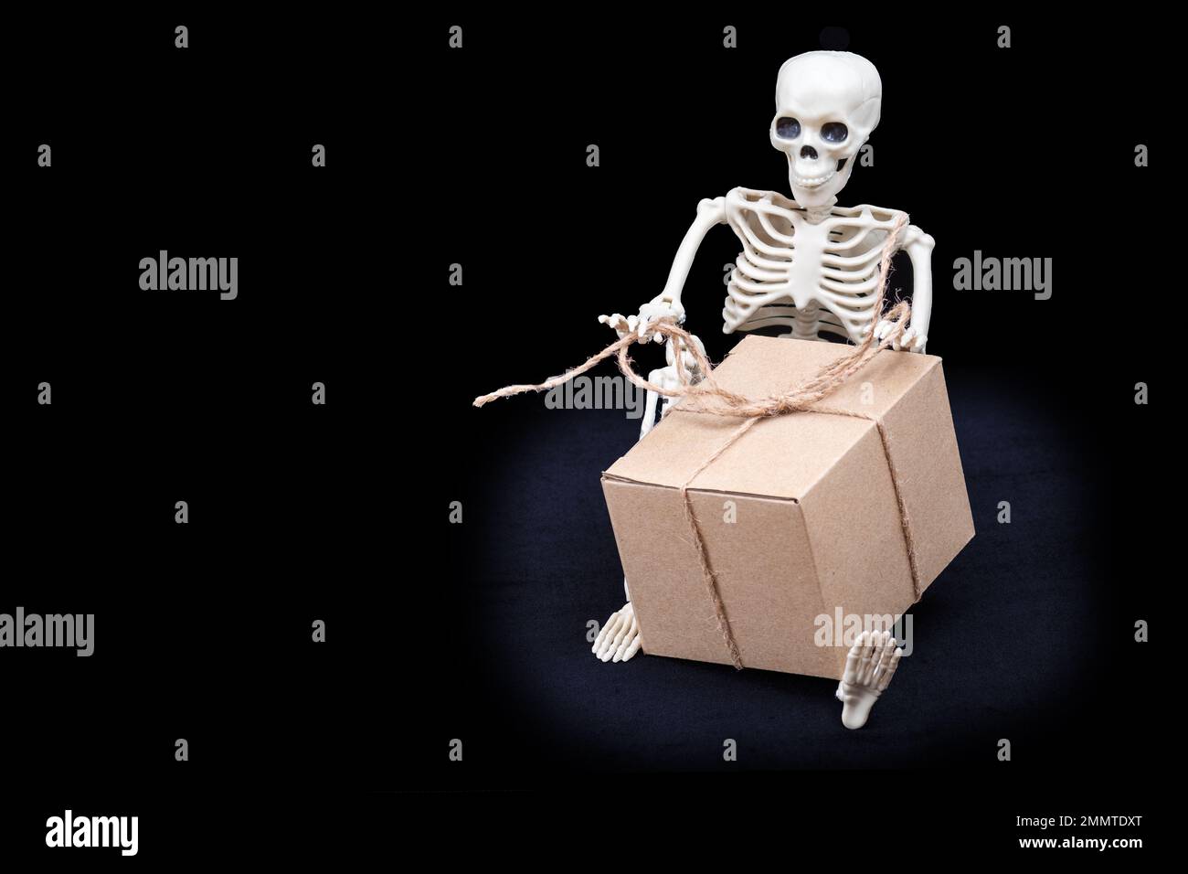 Skeleton holding a gift box on a black background. Gift for the day of ...