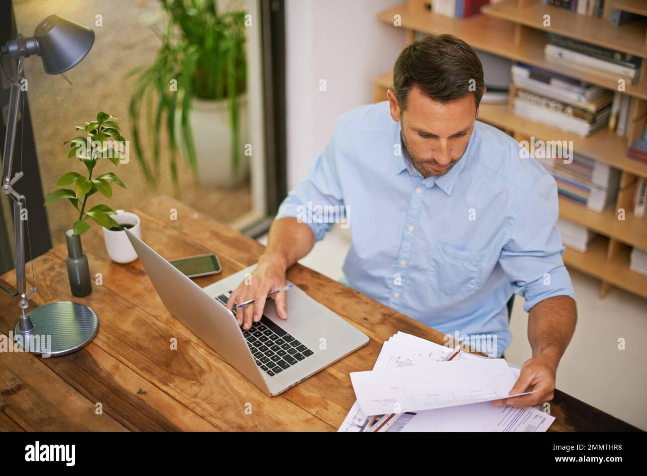 Going over important documentation. a young man working from home Stock ...