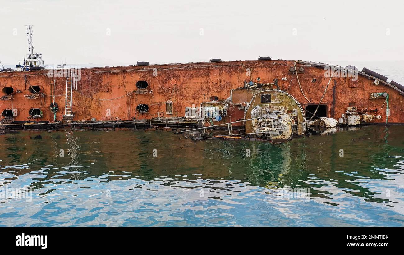 Old rusty oil tanker on its edge in the shallow water. Sunken drowned ...