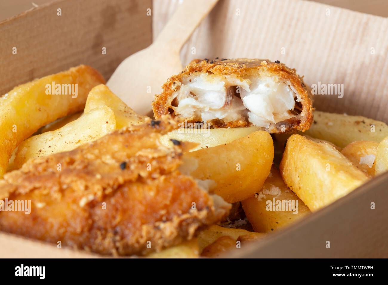 Fish and chips takeaway in a cardboard tray with a wooden fork ...
