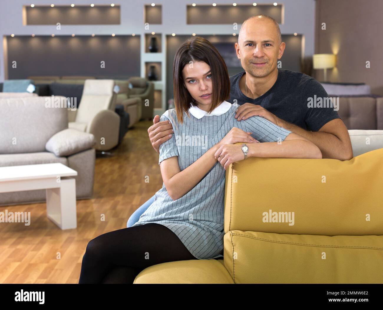 Couple sitting on yellow sofa Stock Photo - Alamy