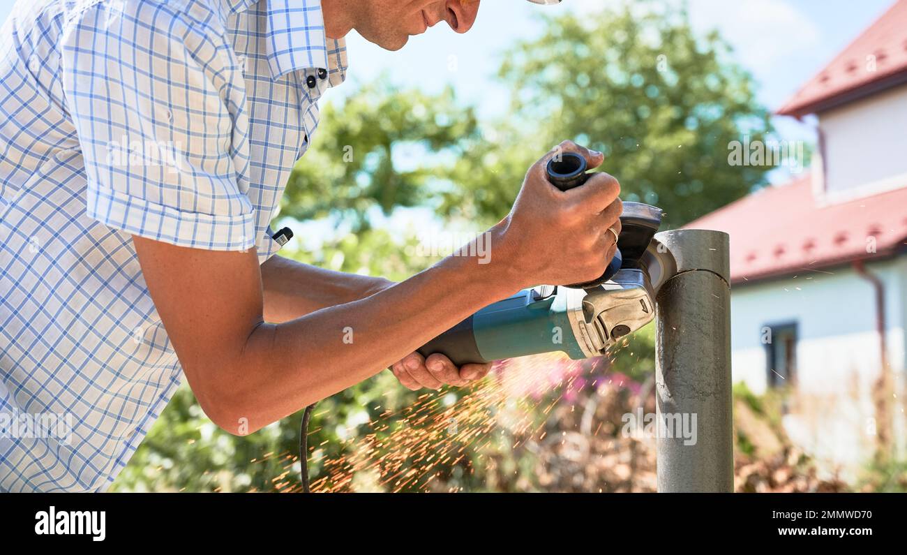 Worker cutting metal pole with grinder for installing solar panels ...