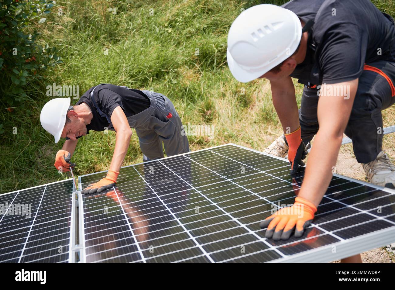 Male workers mounting photovoltaic solar panel system outdoors. Men ...
