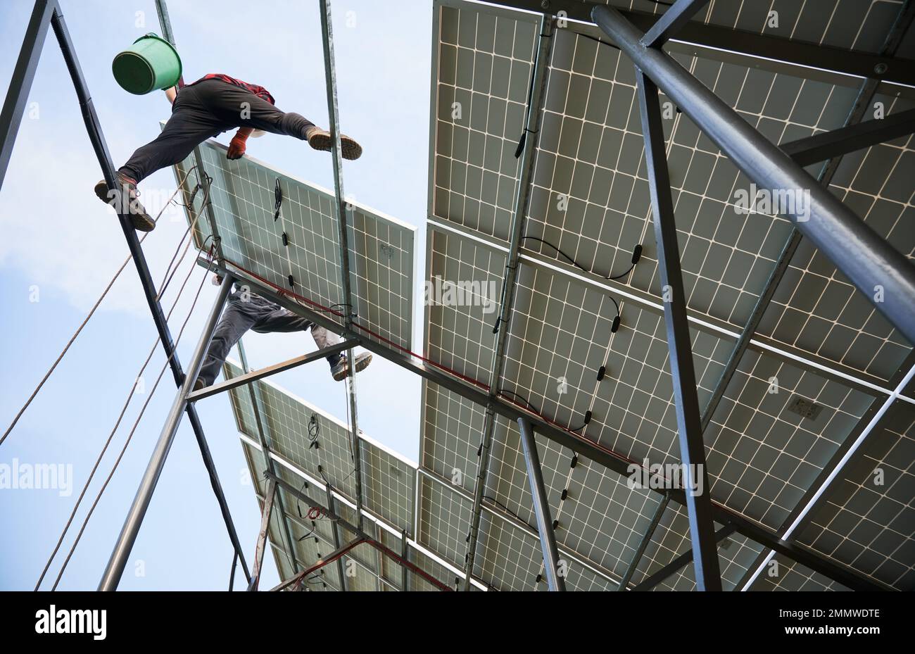 View from below of workers installing photovoltaic solar panel system ...