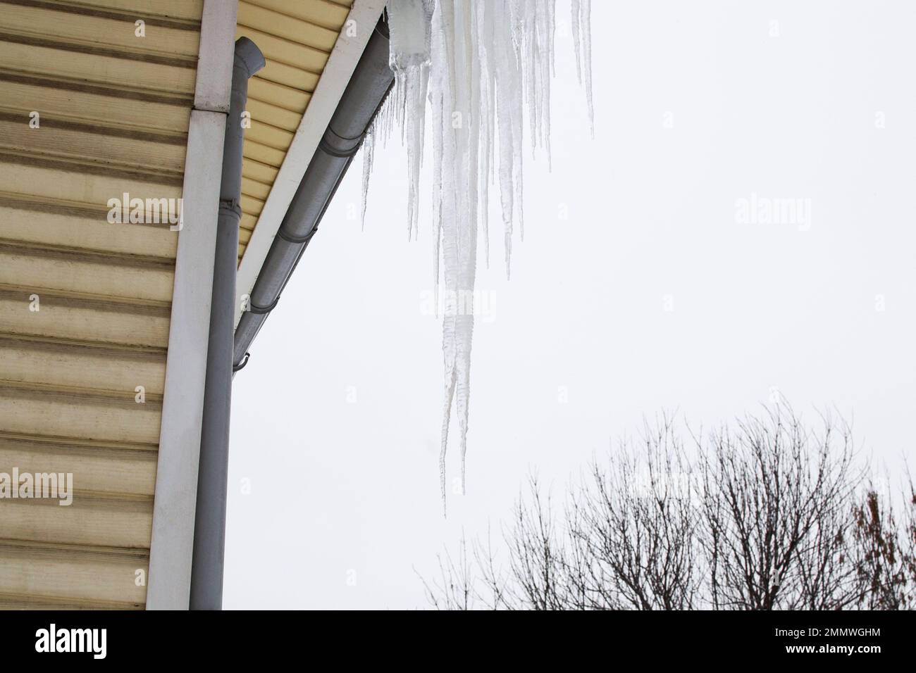 Sharp icicles hanging from eaves of roof. Beautiful transparent icicles ...