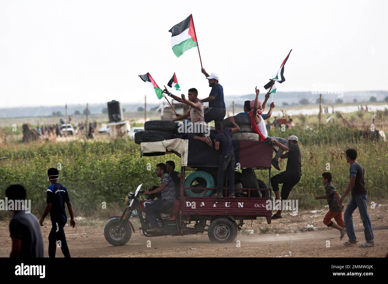 Men wave national flags while riding a motorcycle-taxi, called a Toktok ...