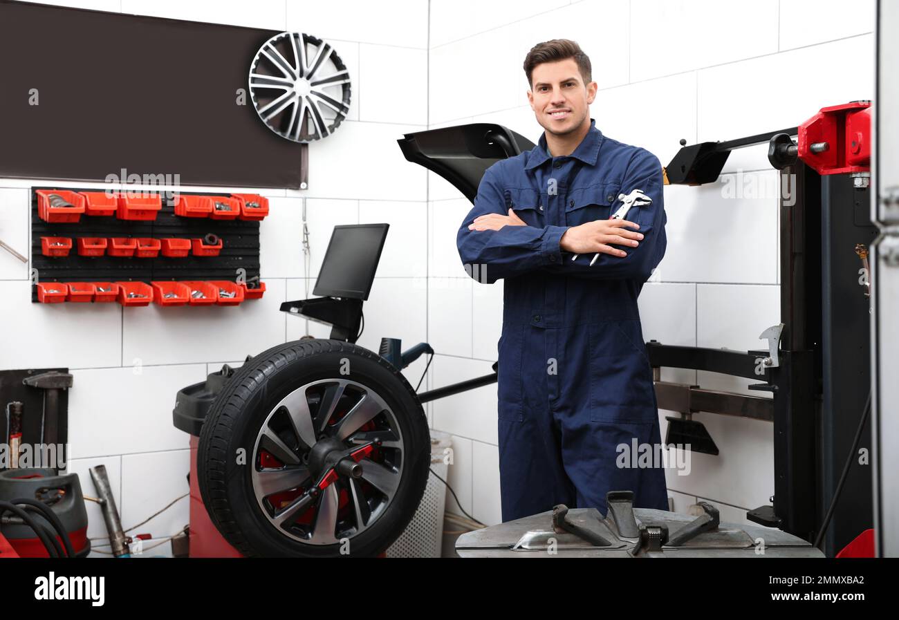 Professional worker with adjustable wrench in shop of modern tire ...