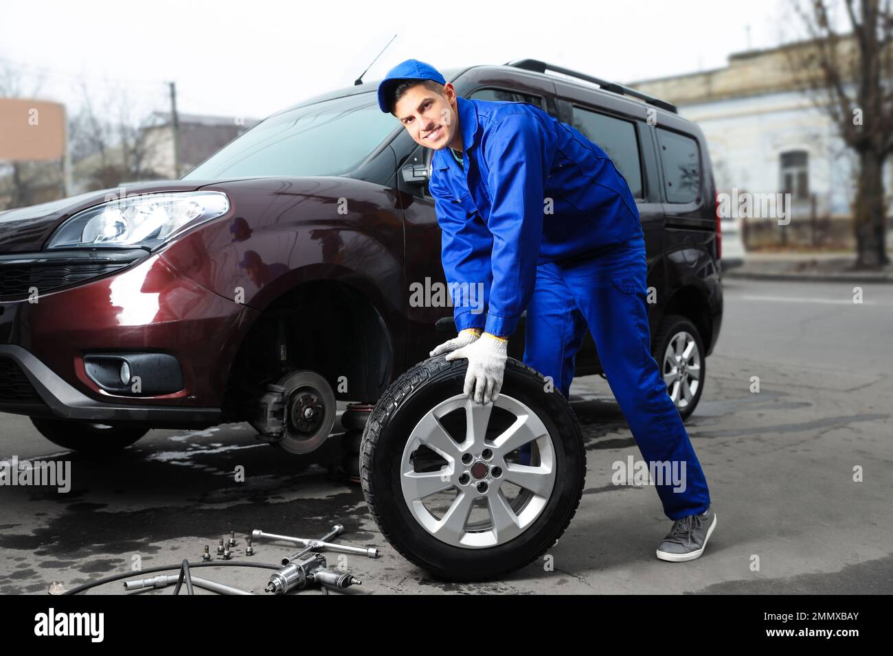 Worker changing car wheel at tire service Stock Photo - Alamy