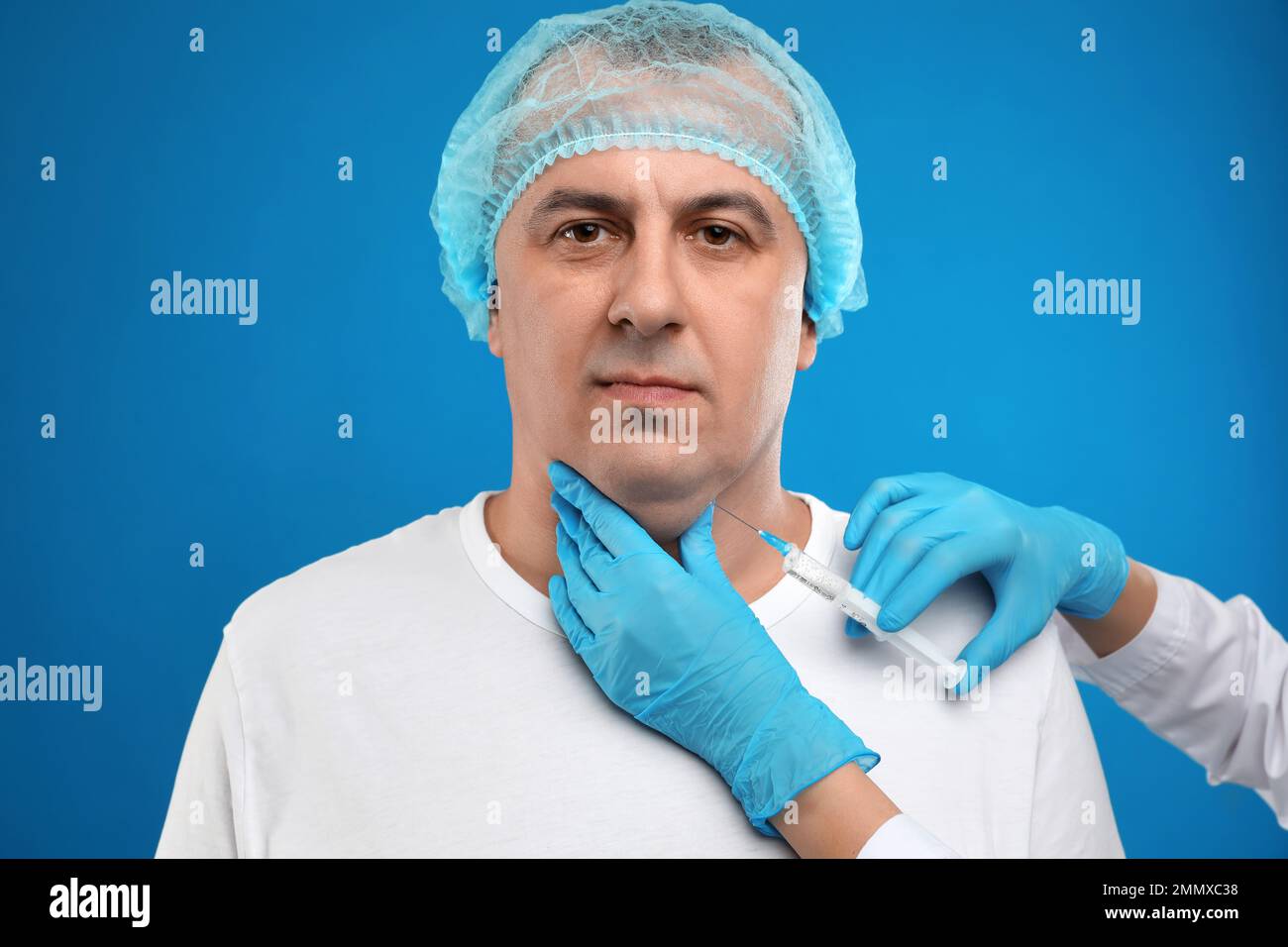 Mature man with double chin receiving injection on blue background ...