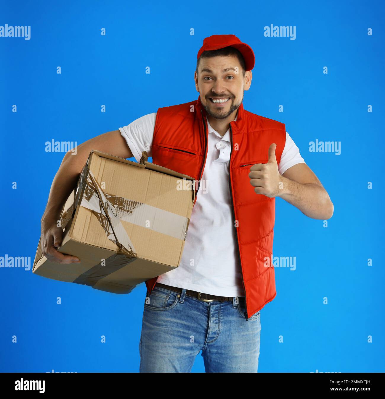 Emotional courier with damaged cardboard box on blue background. Poor ...